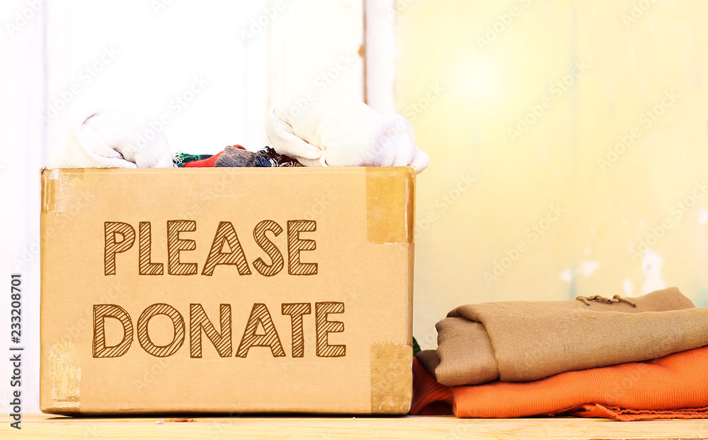 clothes in carton box on wood table for donation, coat drive concept ...