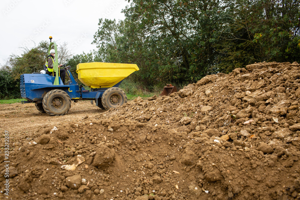 Yellow front tipper dumper working in construction site. Soil pile in ...