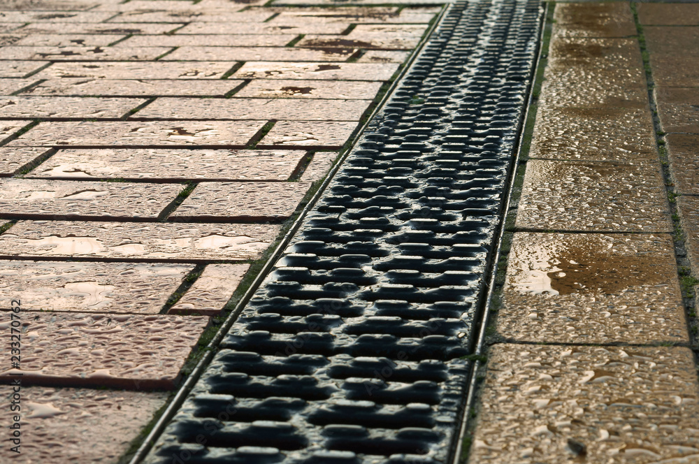 Sidewalk drainage. Grate - rain gutter on the sidewalk. Pathway paved ...