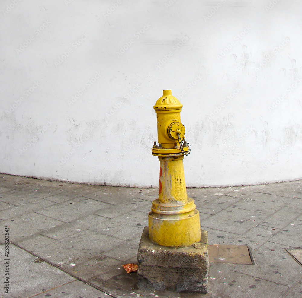 Vintage yellow fire hydrant on the street of city in front of a white ...