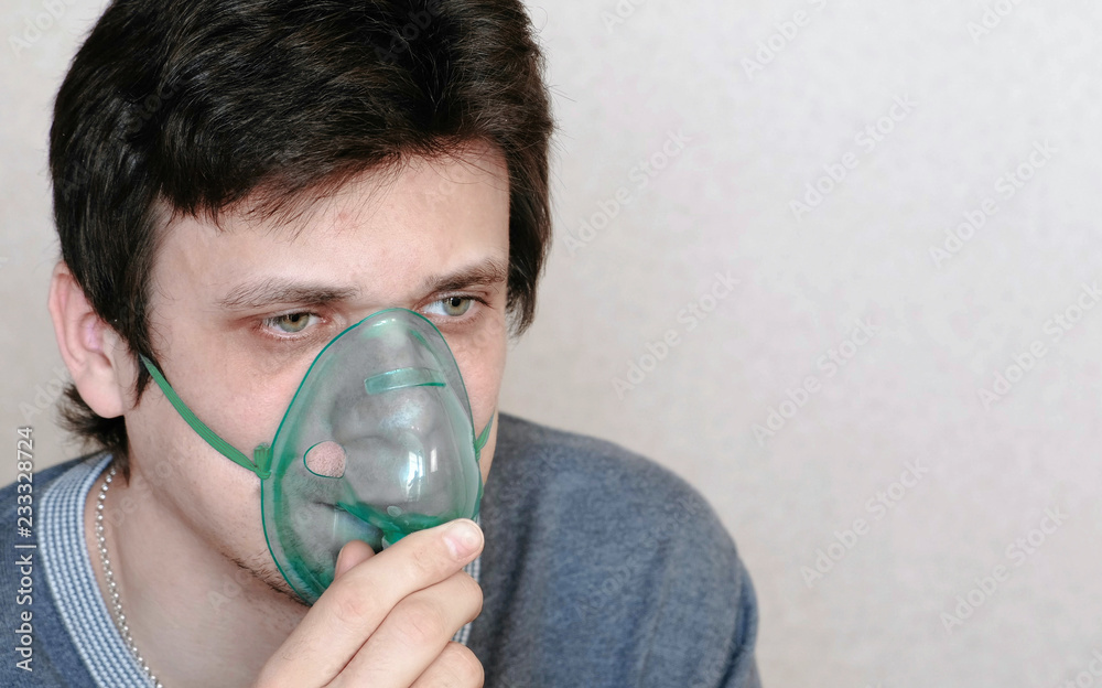 Use nebulizer and inhaler for the treatment. Young man inhaling through ...