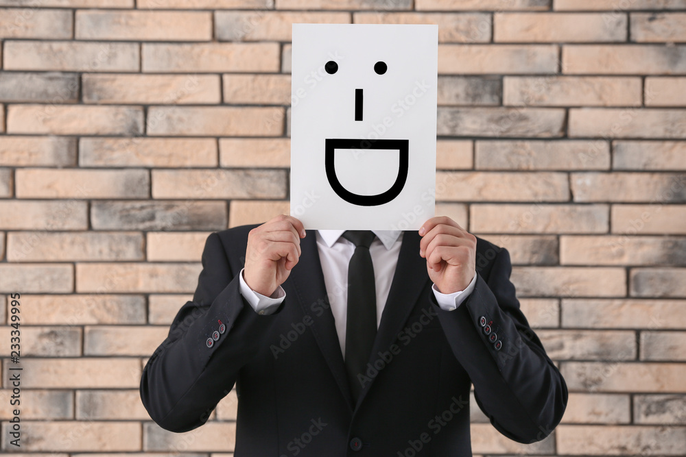 Businessman hiding face behind sheet of paper with drawn emoticon ...