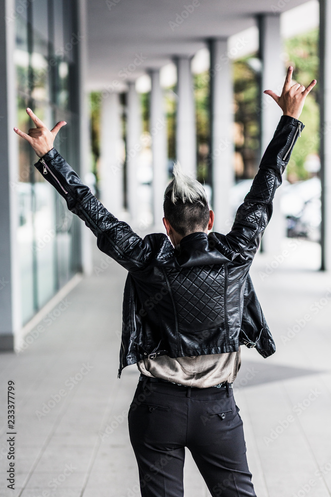 Rear view of punk woman at an arcade showing rock and roll hand sign ...