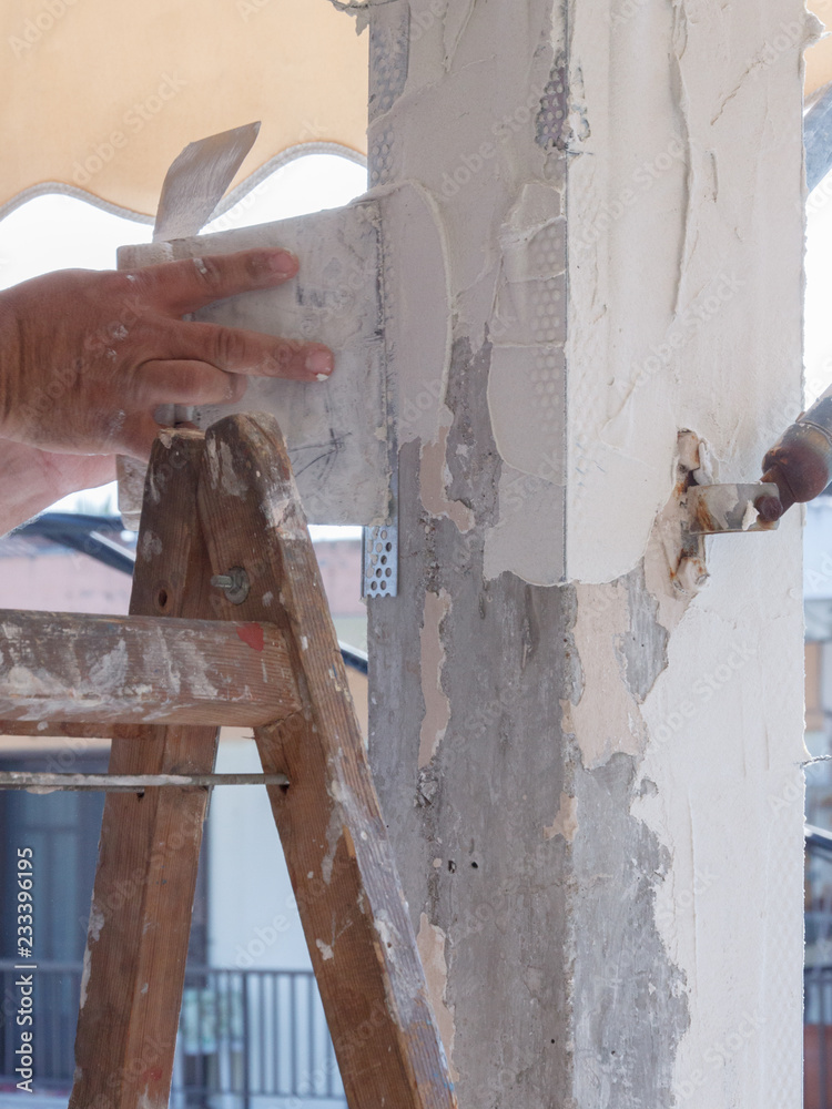 Craftsman is applying plaster on concrete column after reinforcement ...