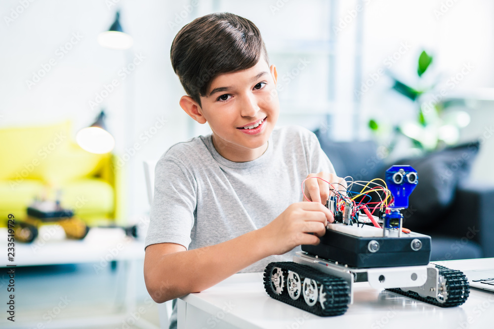 Nice smiling little boy constructing modern robot Stock Photo | Adobe Stock