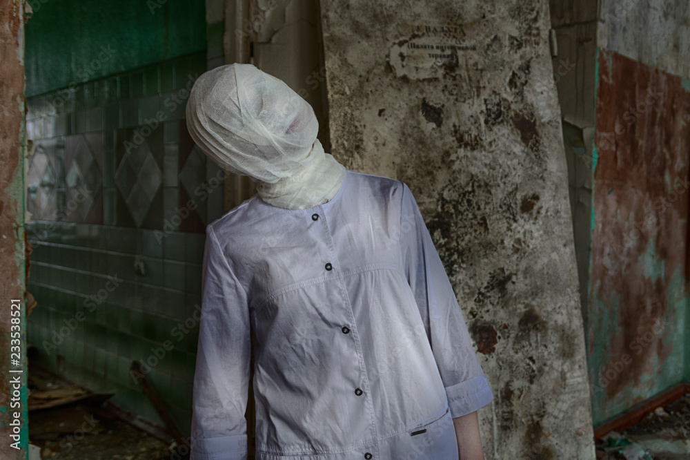 Some man or woman with bandaged face in medical gown inside ruined ...