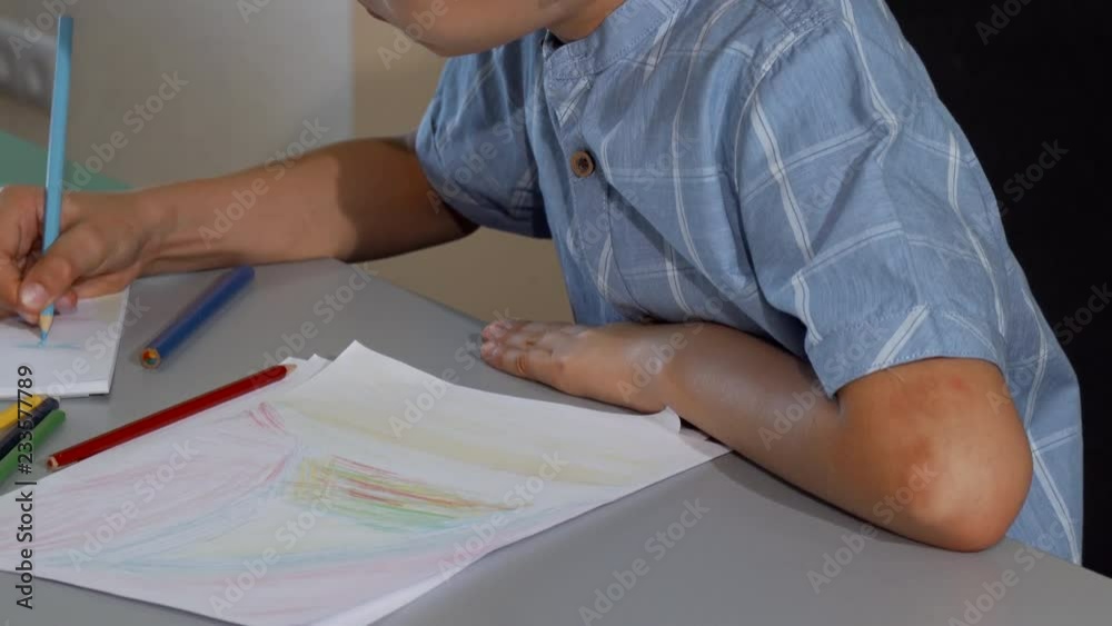 Cute little boy smiling to the camera while drawing. Sliding shot of an ...