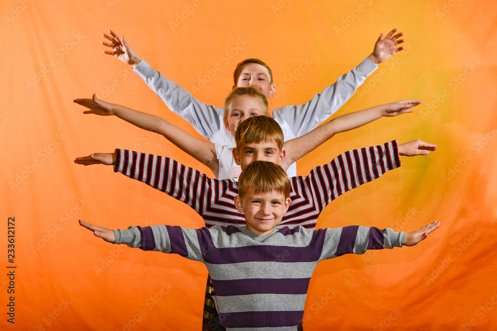 Four children stand in a row and raise their hands to the sides on the ...