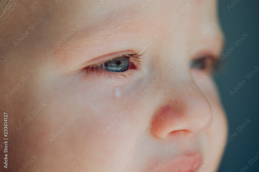 Small and unhappy. Little baby. Baby with tear rolling down his cheek ...