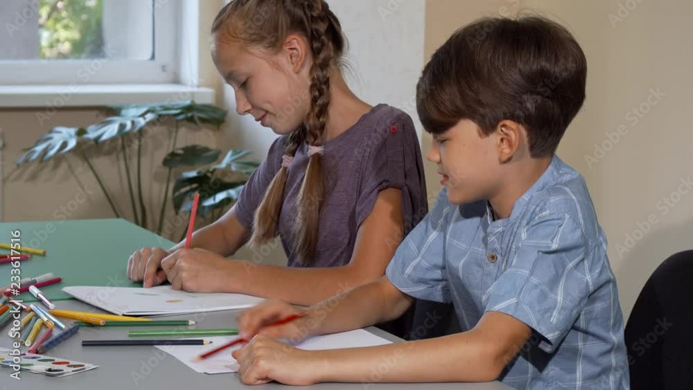 Two kids enjoying talking and drawing at art class together. Little boy ...
