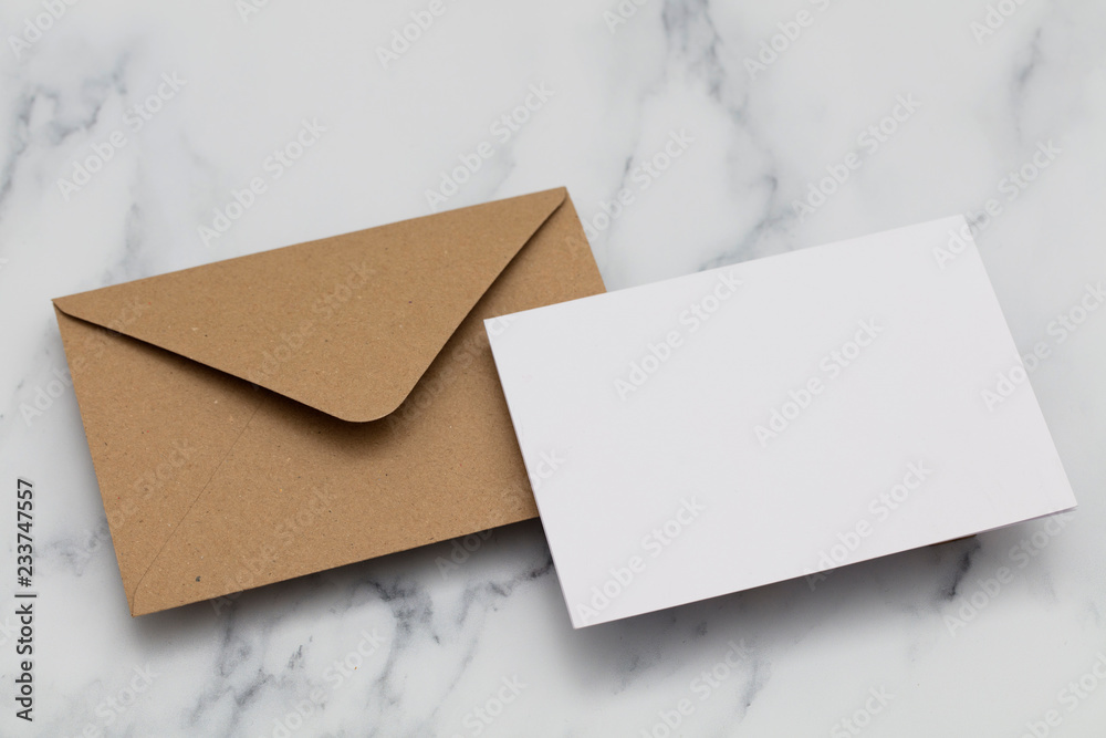 Blank white card with kraft brown paper envelope on marble background ...