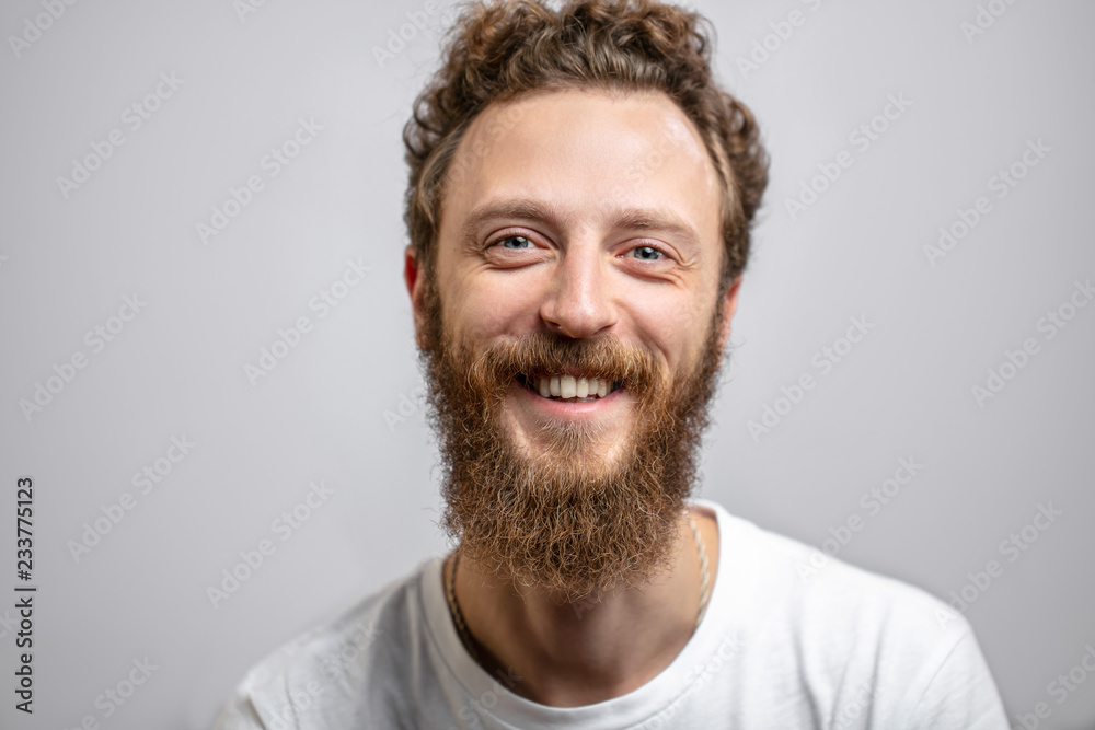 Friendly looking hipster guy smiles happily, has peaceful kind ...