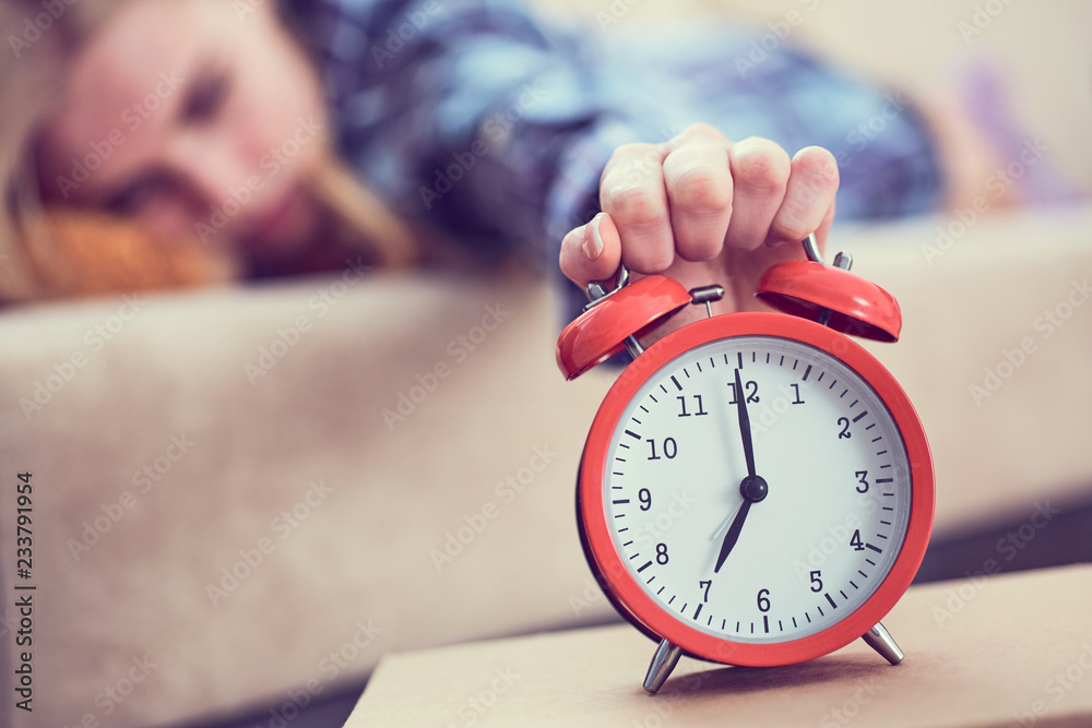 Young girl lies on the couch and stretches her hand to the red alarm ...