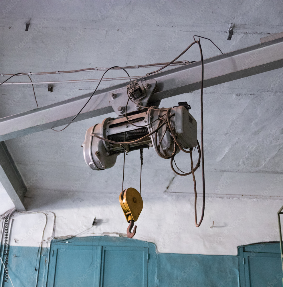 Beam of a crane with an engine and a hook in the hangar, hanging on ...