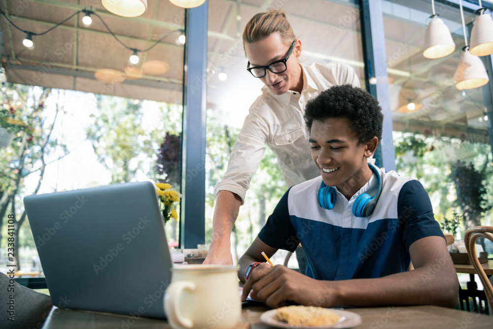 High school student. Nice smart boy taking note while doing his school ...