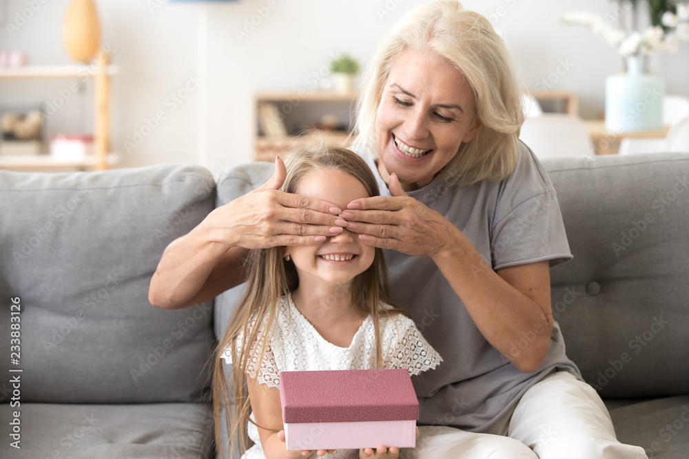 Foto de Loving old grandmother making present to little happy kid girl ...