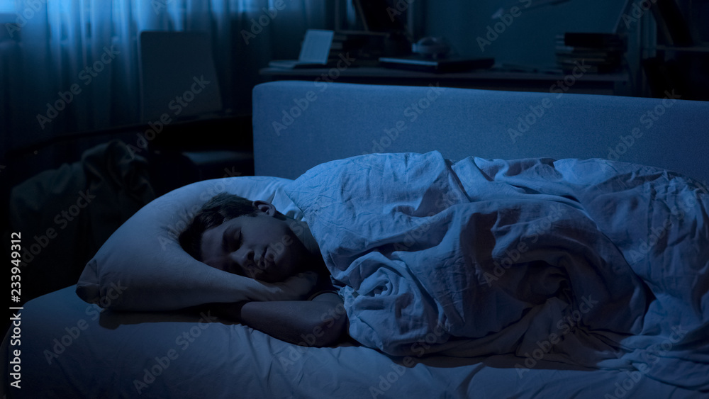 Nice young boy sleeping deep in his bed after hard day at university ...