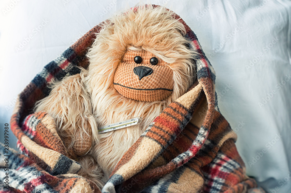 Healthcare and medical concept. Monkey toy lying sick in hospital bed ...