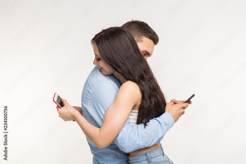 Poster Smartphone addiction concept - young couple hugging and typing ...
