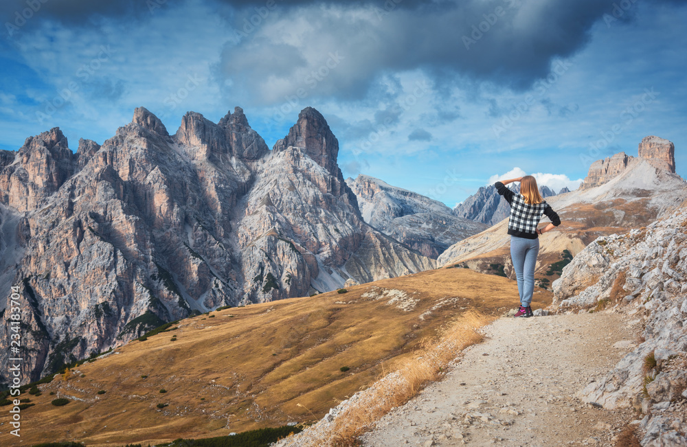 Young woman on the trail is looking on majestic mountains at sunset in ...