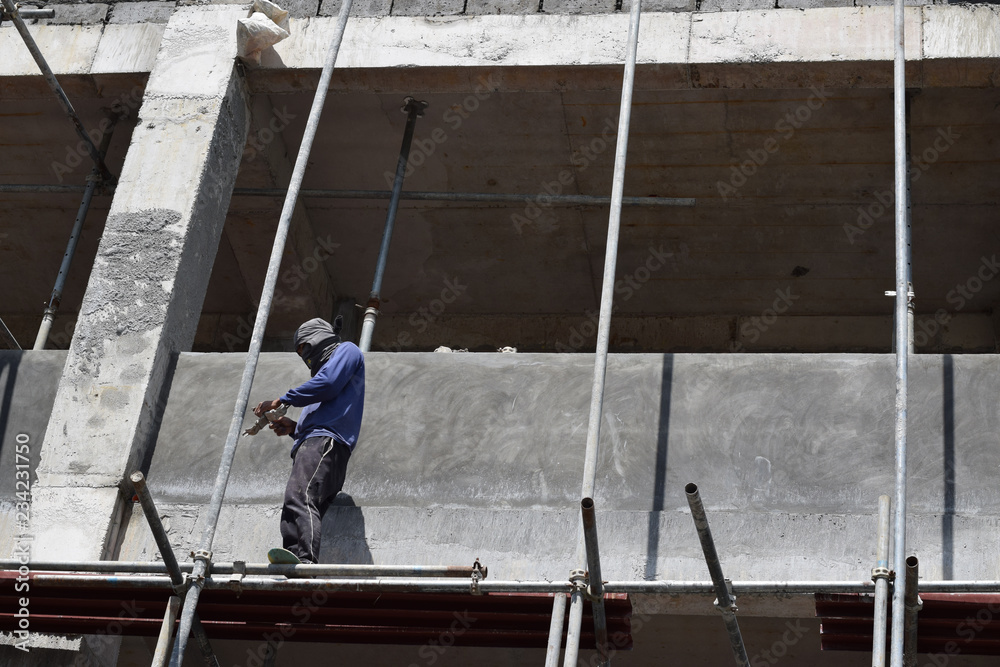 Filipino construction worker installing metal pipe scaffolds on high ...