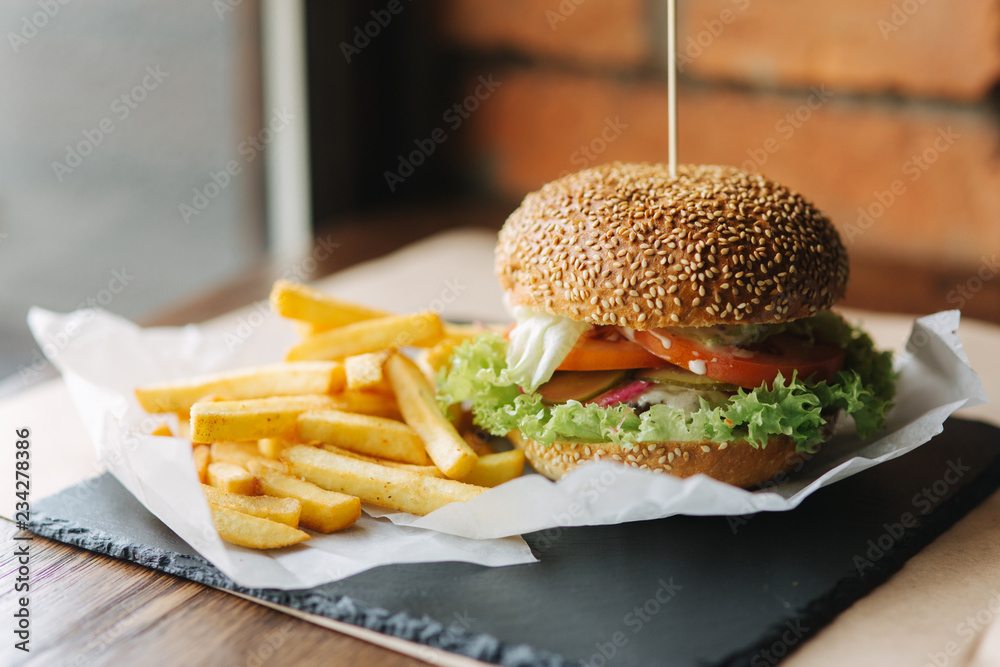 Vegetarian burger with french fries on a black tray in a cafe. Healthy ...