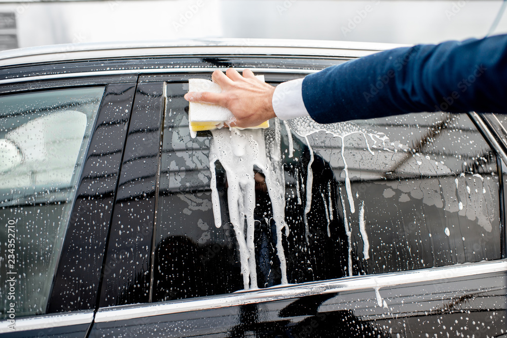 Businessman washing car window with sponge and foam on a self service ...