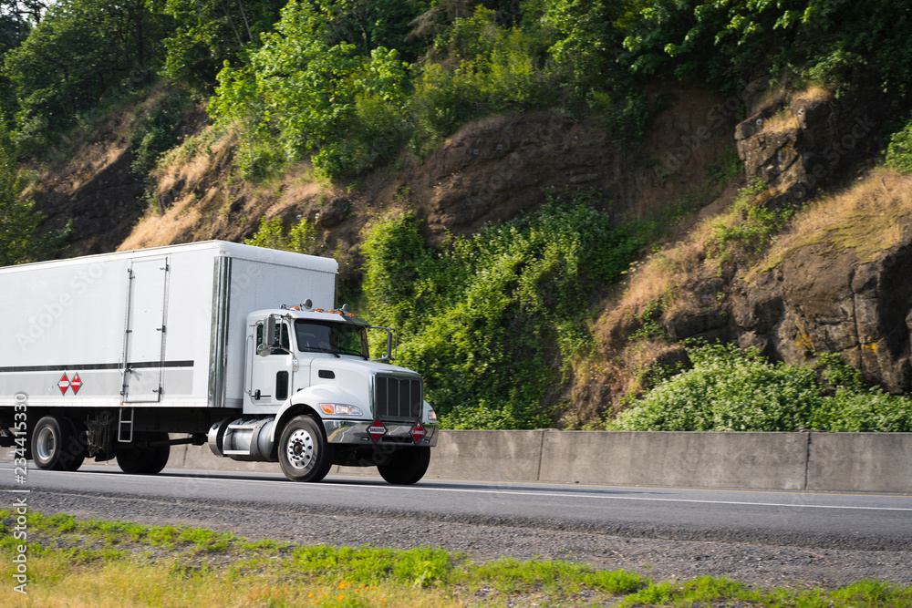 Middle size semi truck with long box trailer transporting flammable ...