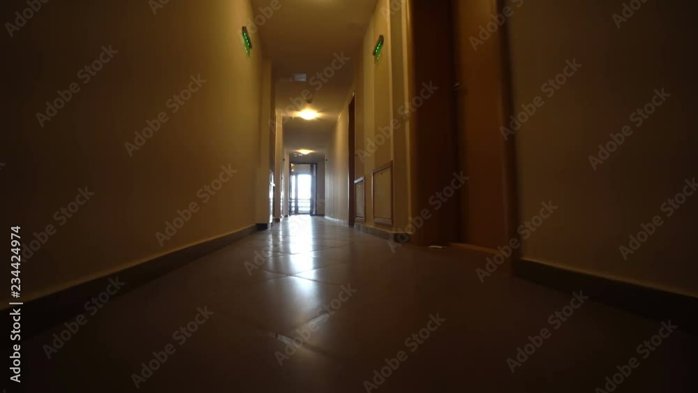 Low angle walk move through long, empty dark building corridor ...