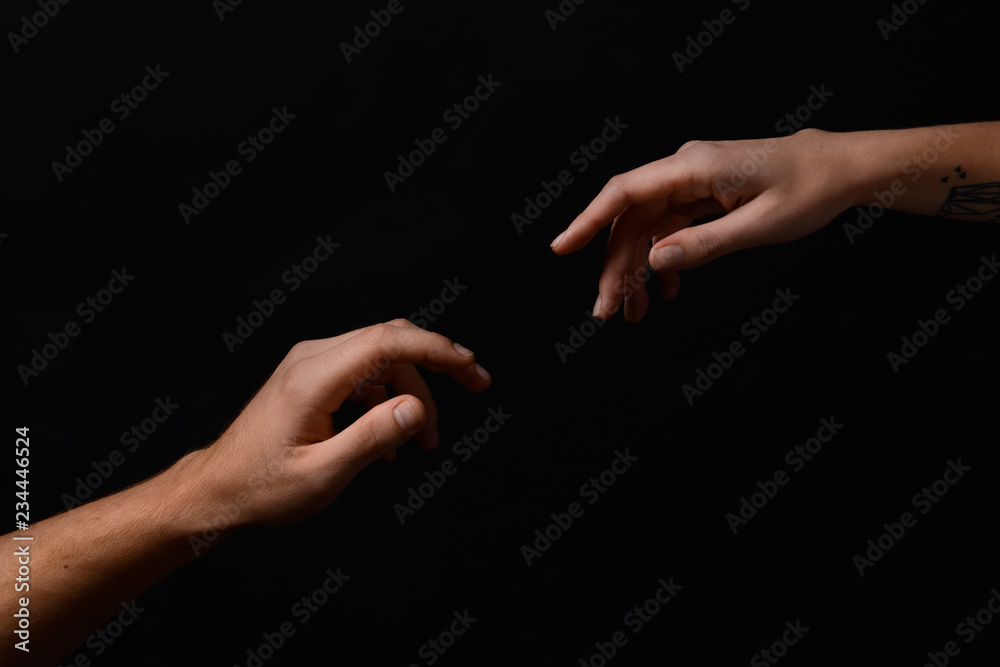 Male and female hands reaching out to each other on dark background ...