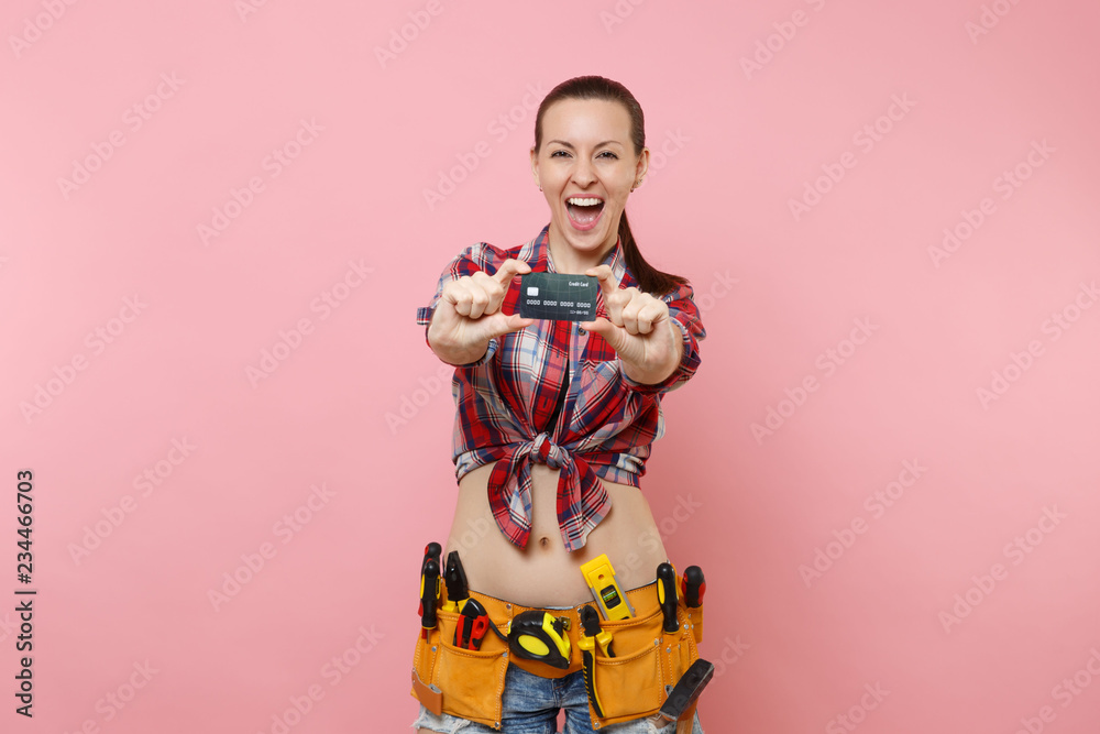 Young smiling handyman woman in plaid shirt, denim shorts, kit tools ...