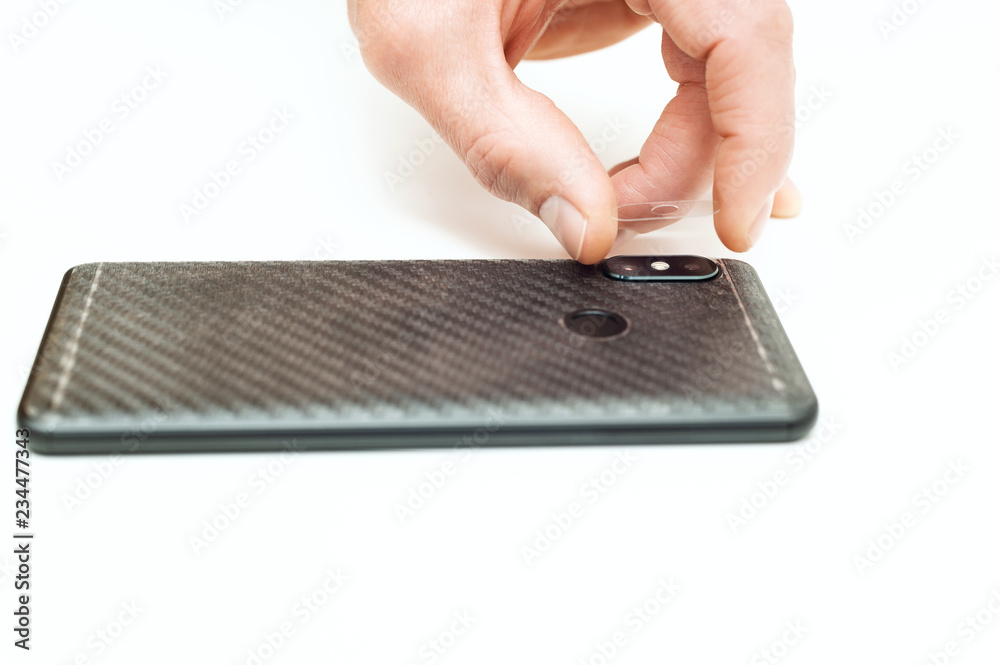 Installing a protective glass on the back lens of the smartphone. Stock ...