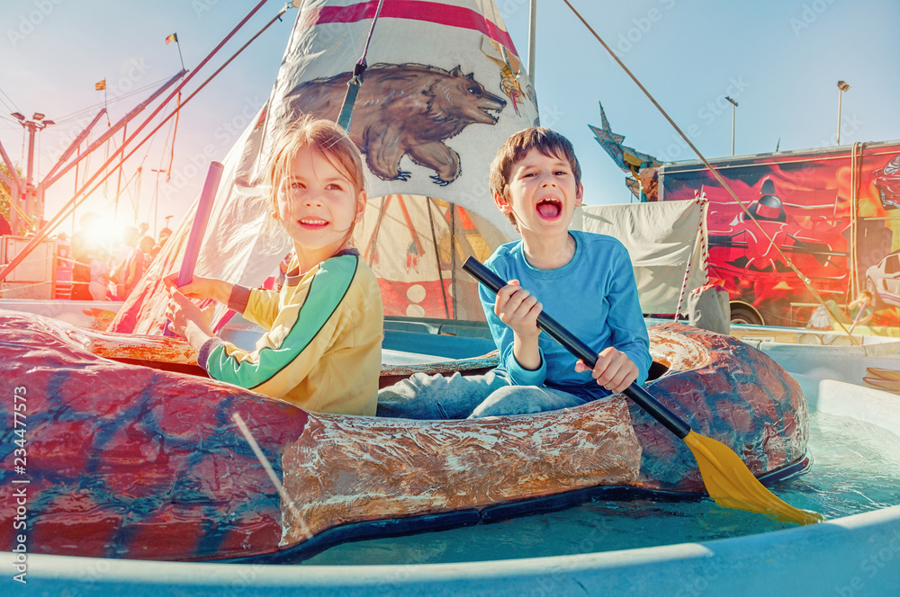 Children having fun at amusement park. Ride on canoe. Happy childhood ...