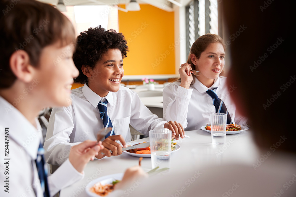 Group Of High School Students Wearing Uniform Sitting Around Table And ...
