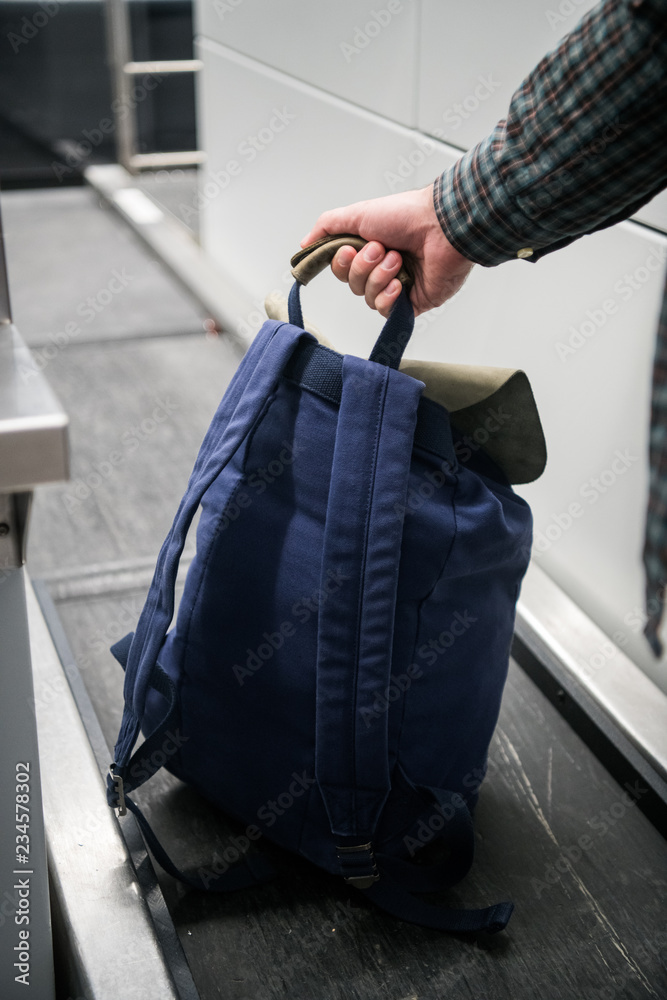 Man's hand with a backpack on luggage conveyor belt system at check in ...