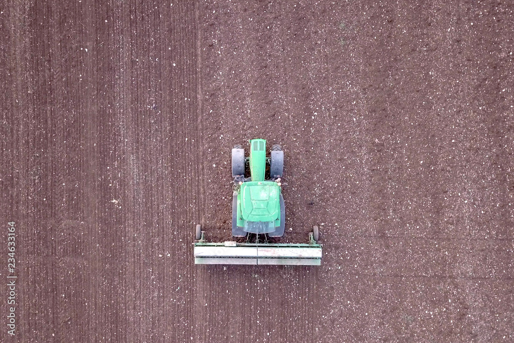 Green Tractor cultivating and seeding a dry field - Top down aerial ...
