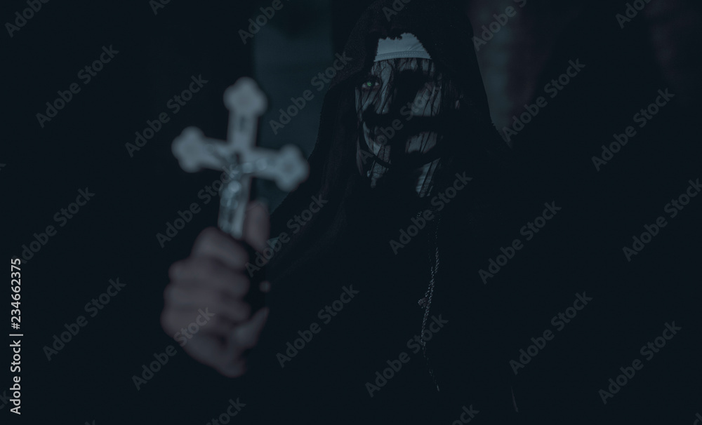 Woman is standing in a darkness with a cross in her hand in an image of ...