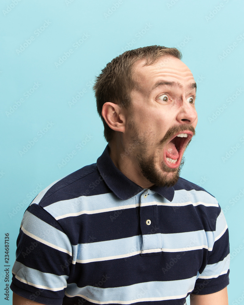 The surprised and astonished young man screaming with open mouth ...