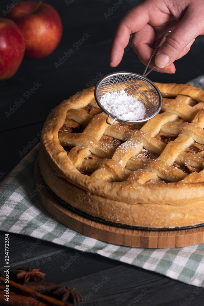 Hands decorating apple pie with powdered sugar. Homemade dessert. Baked ...