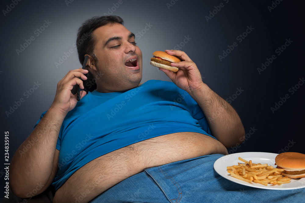 Foto de Relaxed obese man with belly visible out of his shirt eating ...