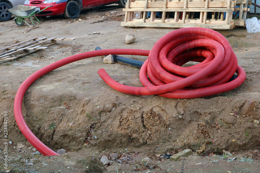 Red armed plastic pipes for a drainage and melioration lie on a city ...