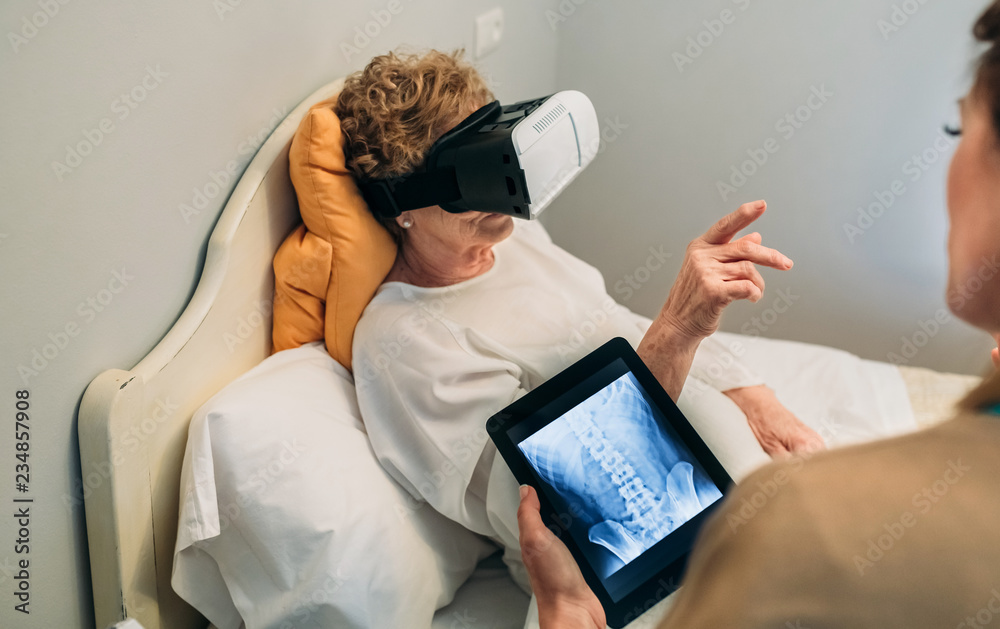 Older patient using virtual reality glasses to see her spine while ...