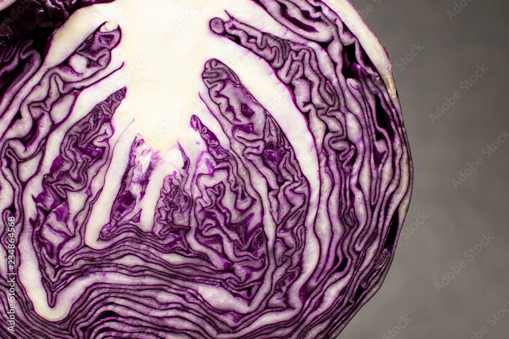 red cabbage ball cut in half with all the leaves on a black granite ...