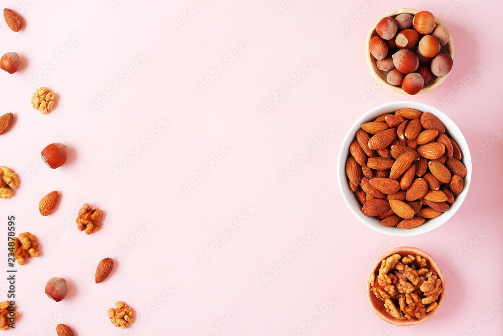 Assortment of nuts in bowls. Almond, hazelnut, walnut on pink ...