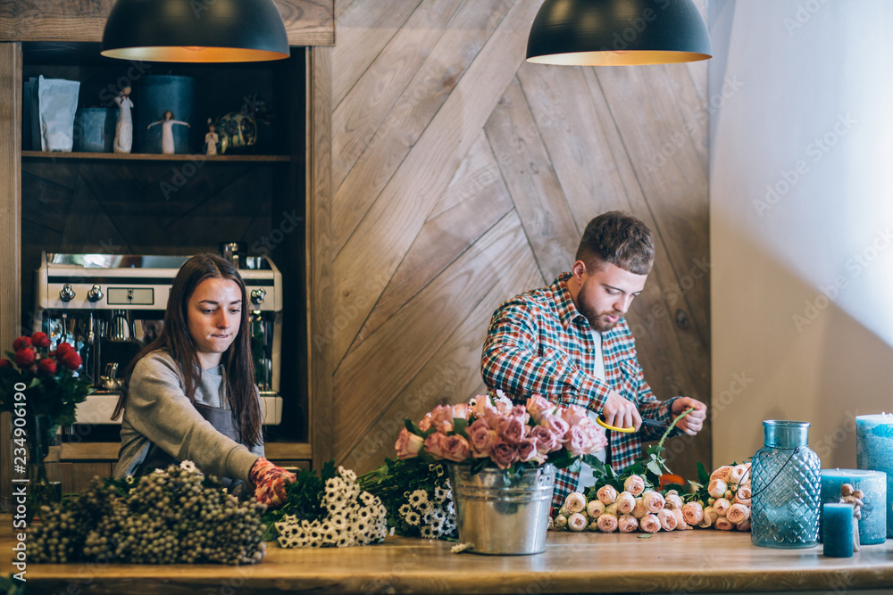 Team of two florists man and woman working with flowers while standing ...