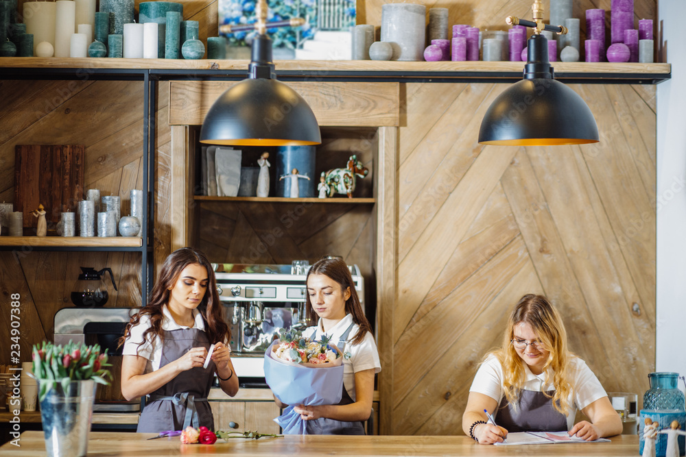 Team of three females florists working with flowers while standing ...