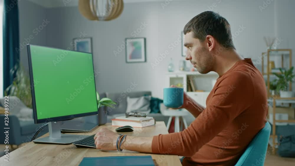 Handsome Smiling Man Sitting at His Desk at Home Uses Personal Computer ...