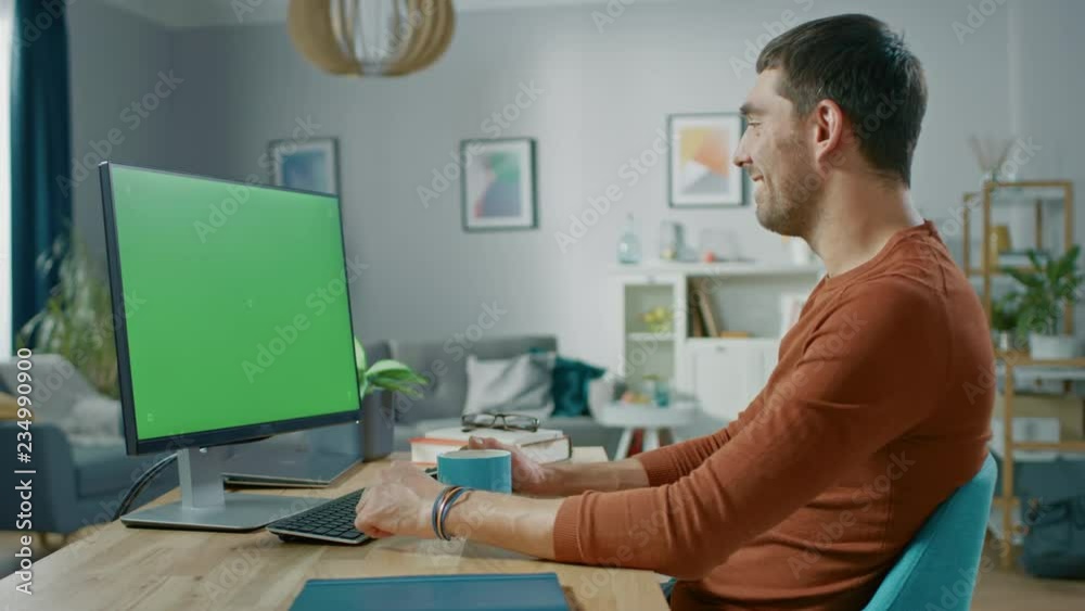 Handsome Smiling Man Sitting at His Desk at Home Uses Personal Computer ...