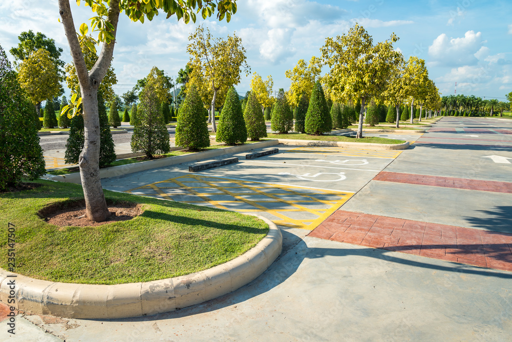 Empty space in city park outdoor concrete parking lot area with blue sky in summer season. Green ...