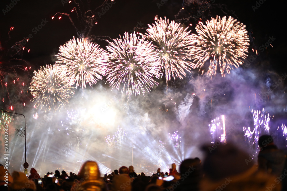 Crowd of spectators of festive salute and light show in the night sky ...